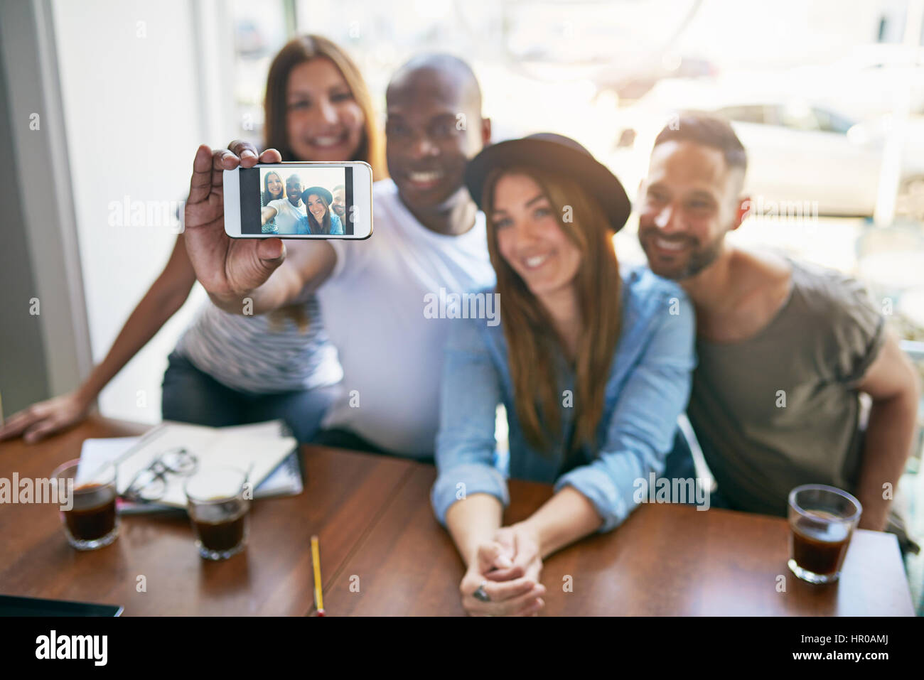 Young four people sitting at table and making self portrait against ...