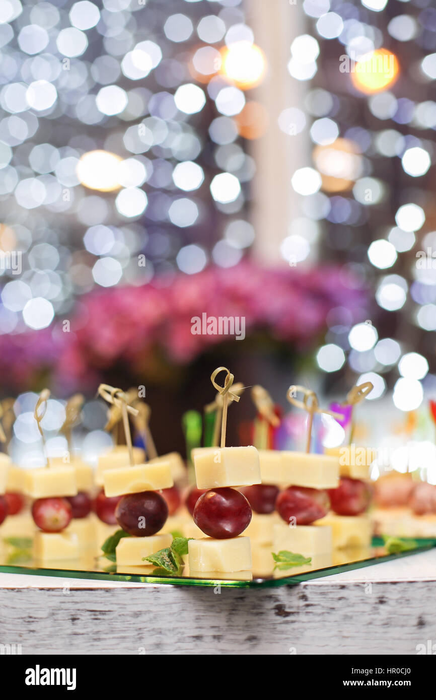 Appetizer of grape, pineapple cubes and cheese are on wooden skewers ...