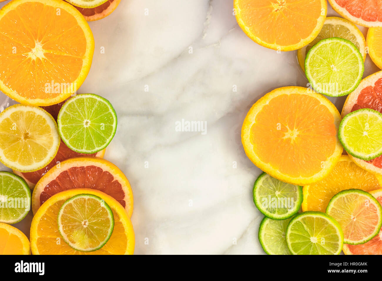 Vibrant juicy citrus fruits on a white marble texture with copy space ...