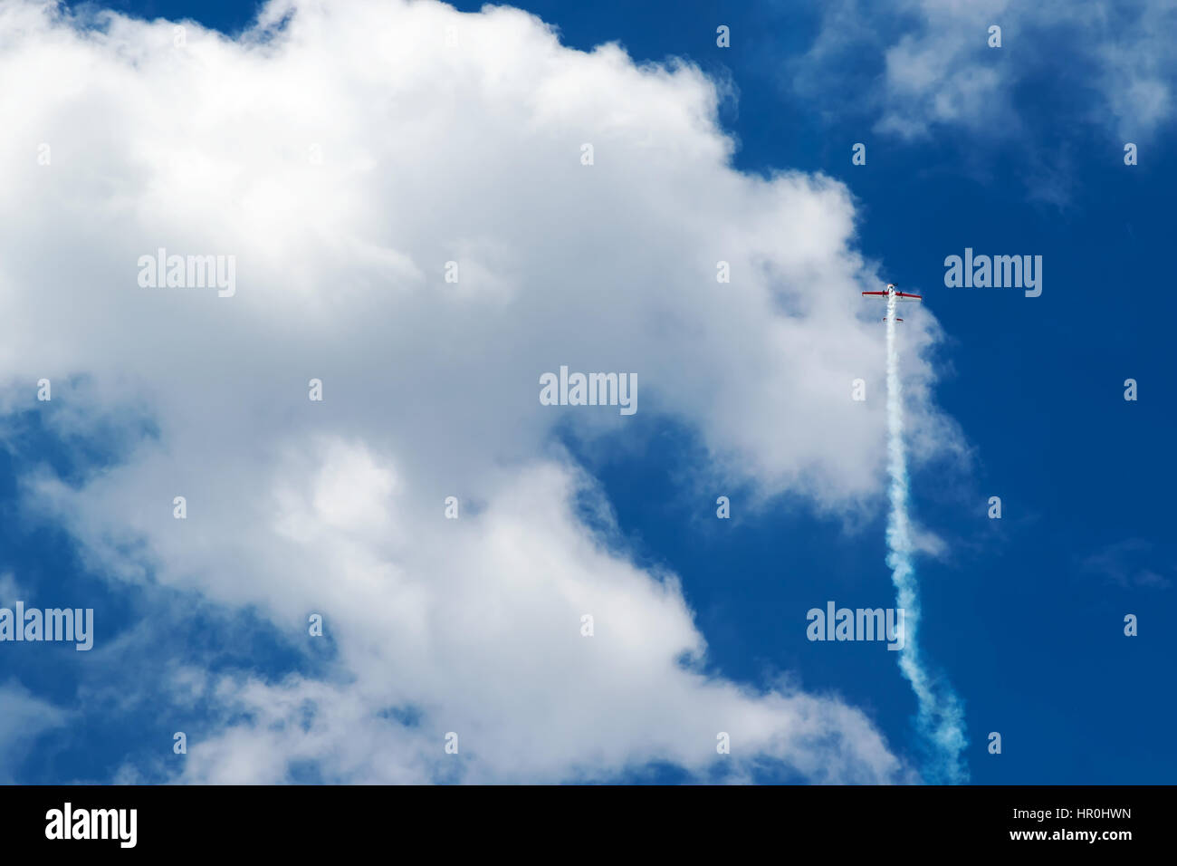 Small sports plane flies straight up into the blue sky with clouds and ...