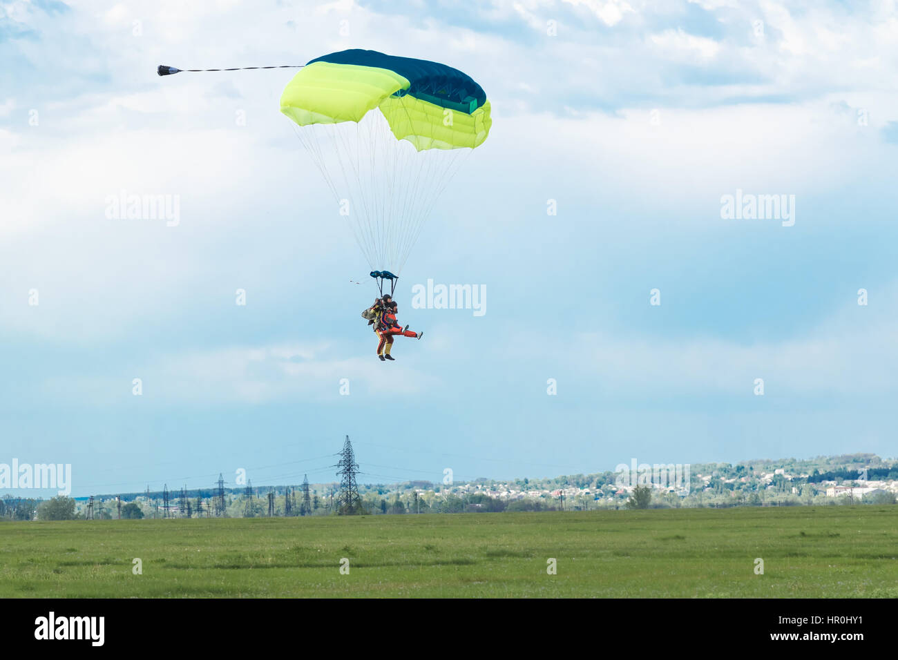 Two people flying in a tandem with a parachute landing on the ground ...