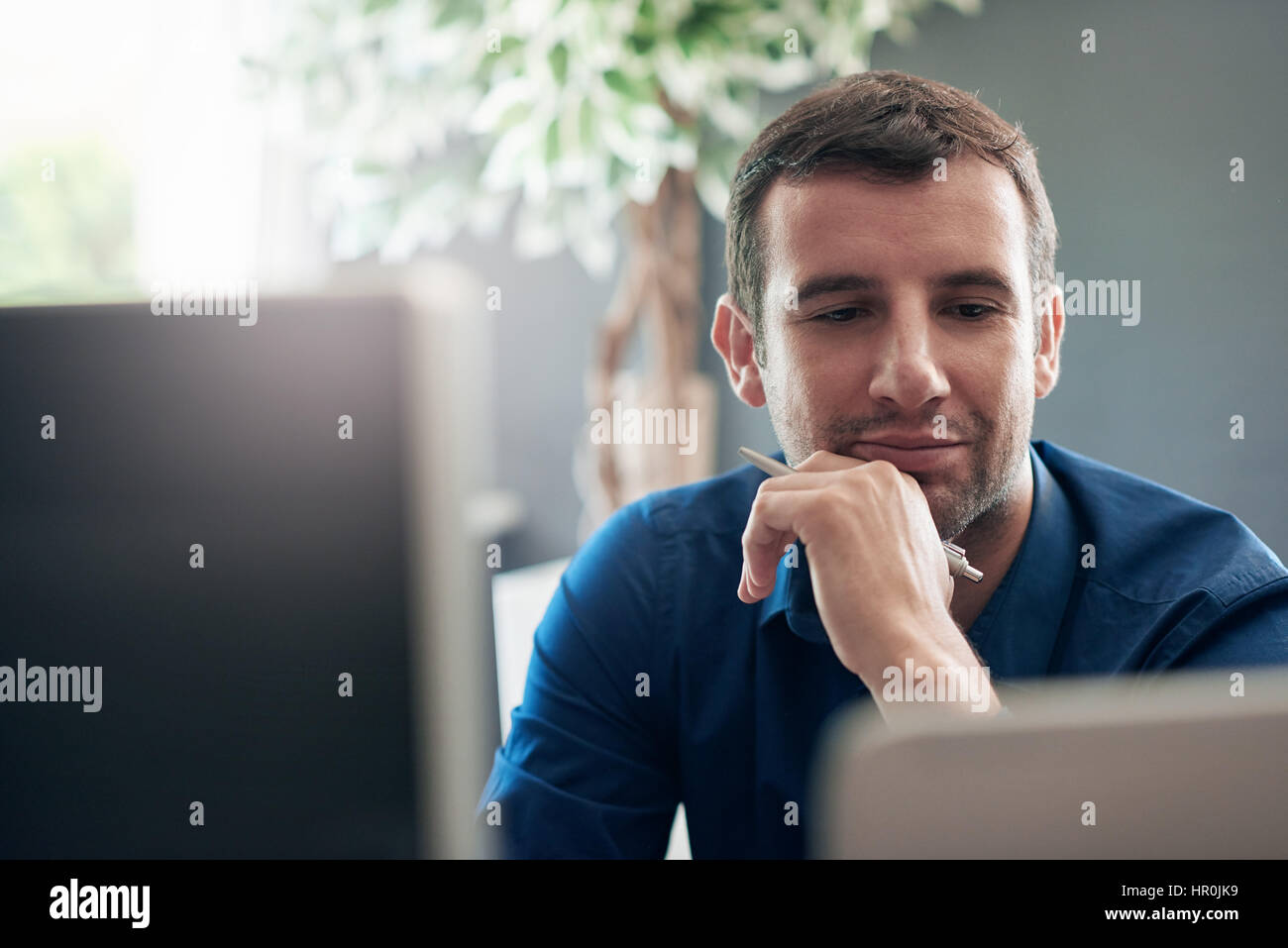 Confident and successful businessman sitting at a desk deep in thought ...