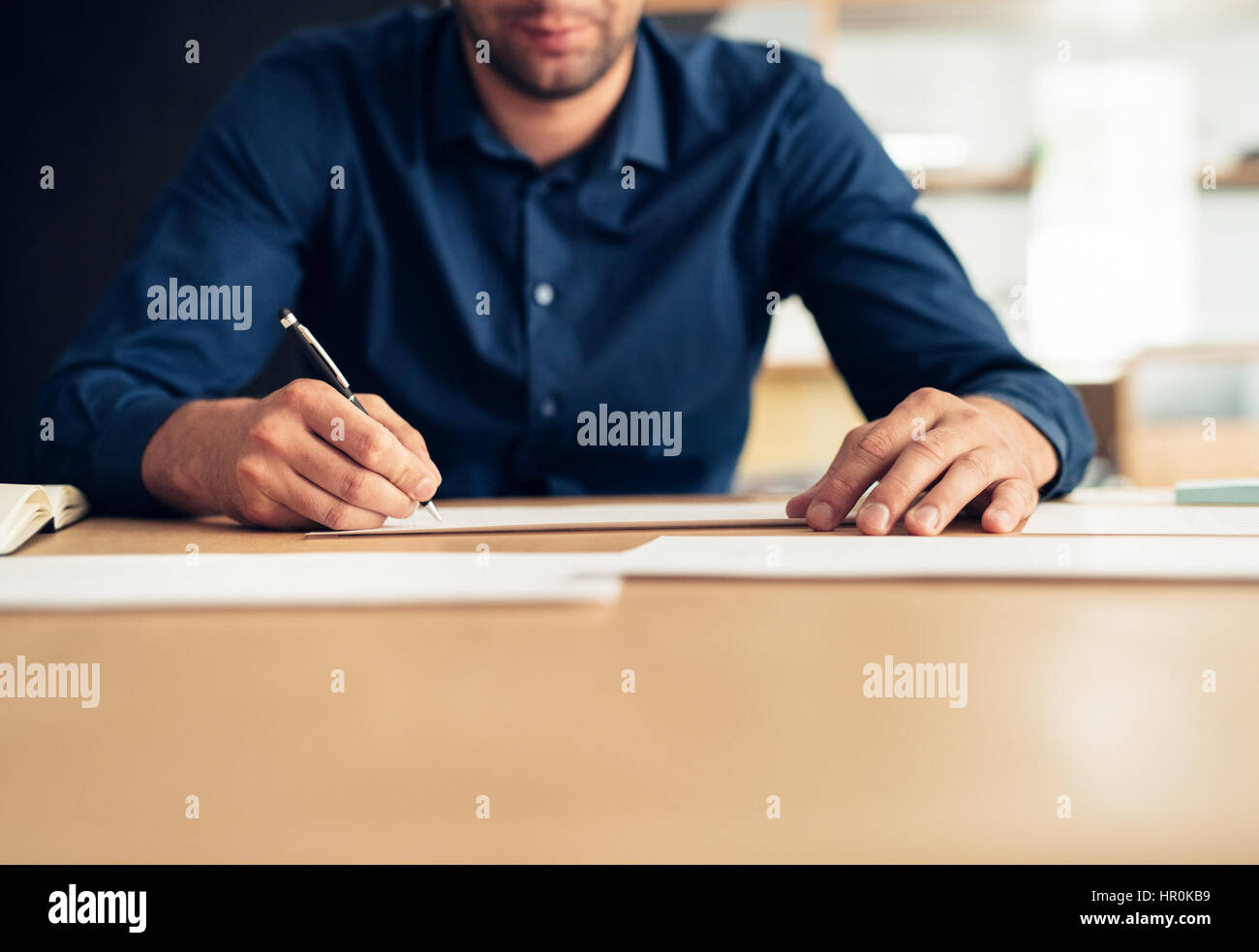 Closeup of a successful young businessman writing on documents while ...