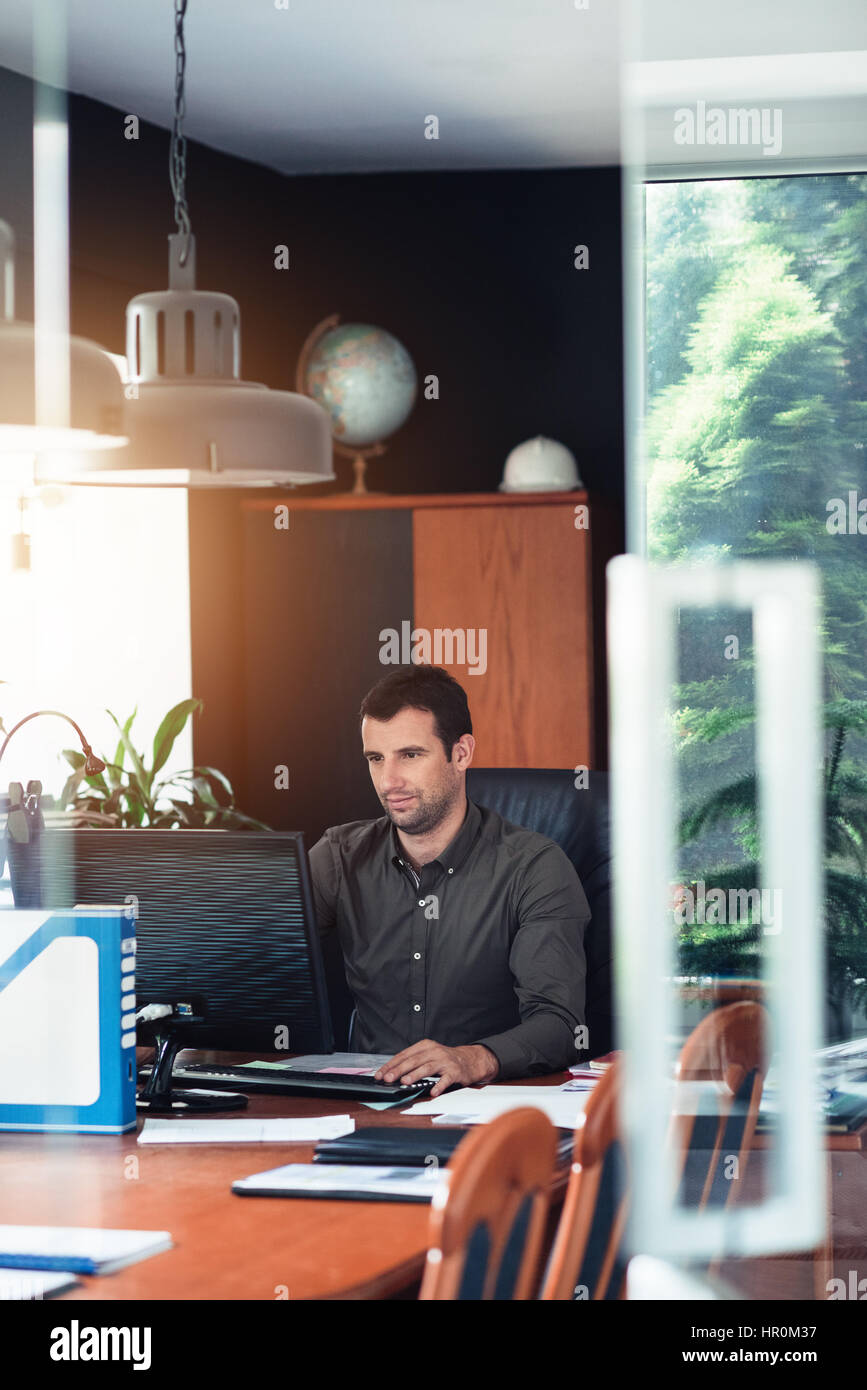 Confident and successful young businessman sitting at a desk deep in ...