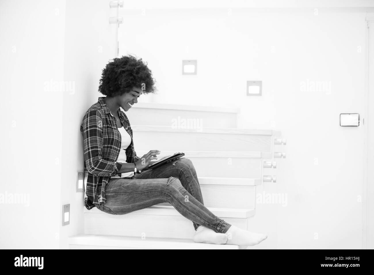Attractive young black woman using her electronic tablet while sitting ...