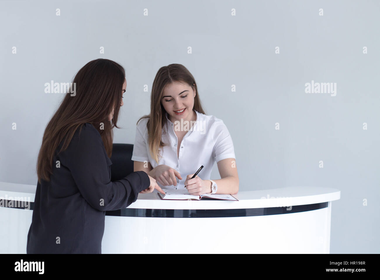 young female receptionist at medical clinic or hospital discussing ...