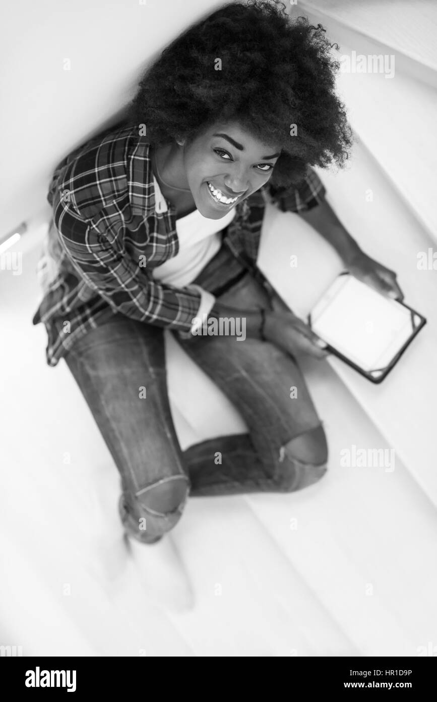Attractive young black woman using her electronic tablet while sitting ...