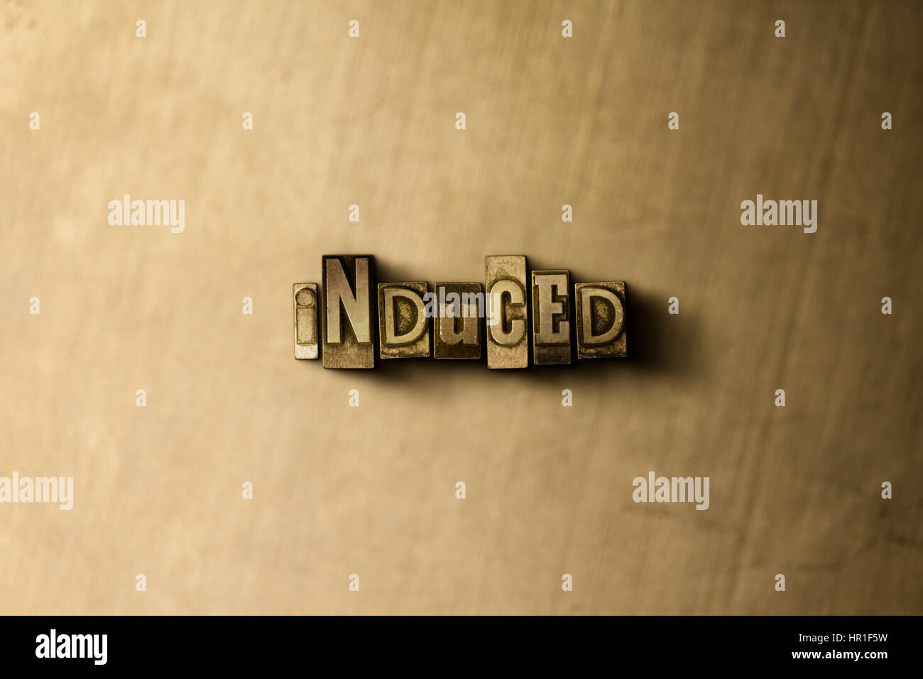 INDUCED - close-up of grungy vintage typeset word on metal backdrop ...