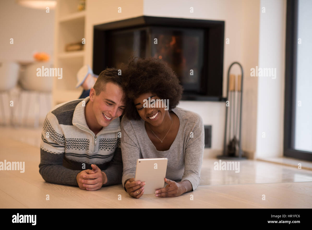 beautiful young multiethnic couple using tablet computer on the floor ...