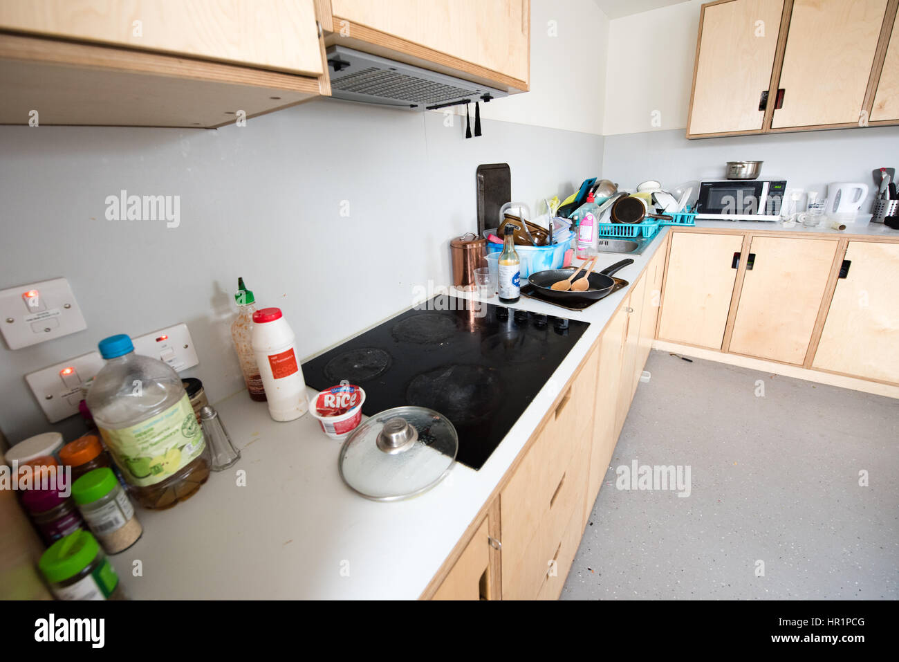 Dirty messy student shared kitchen with piles of washing up by the sink ...