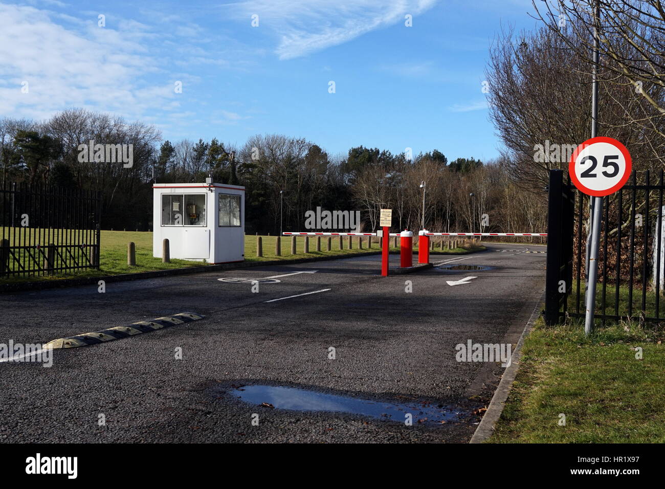 Security barrier, speed limit sign and guard hut at entrance to office ...