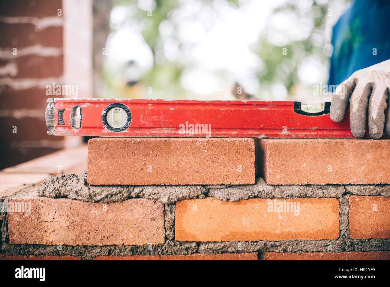 construction worker, bricklayer or mason laying bricks and creating ...