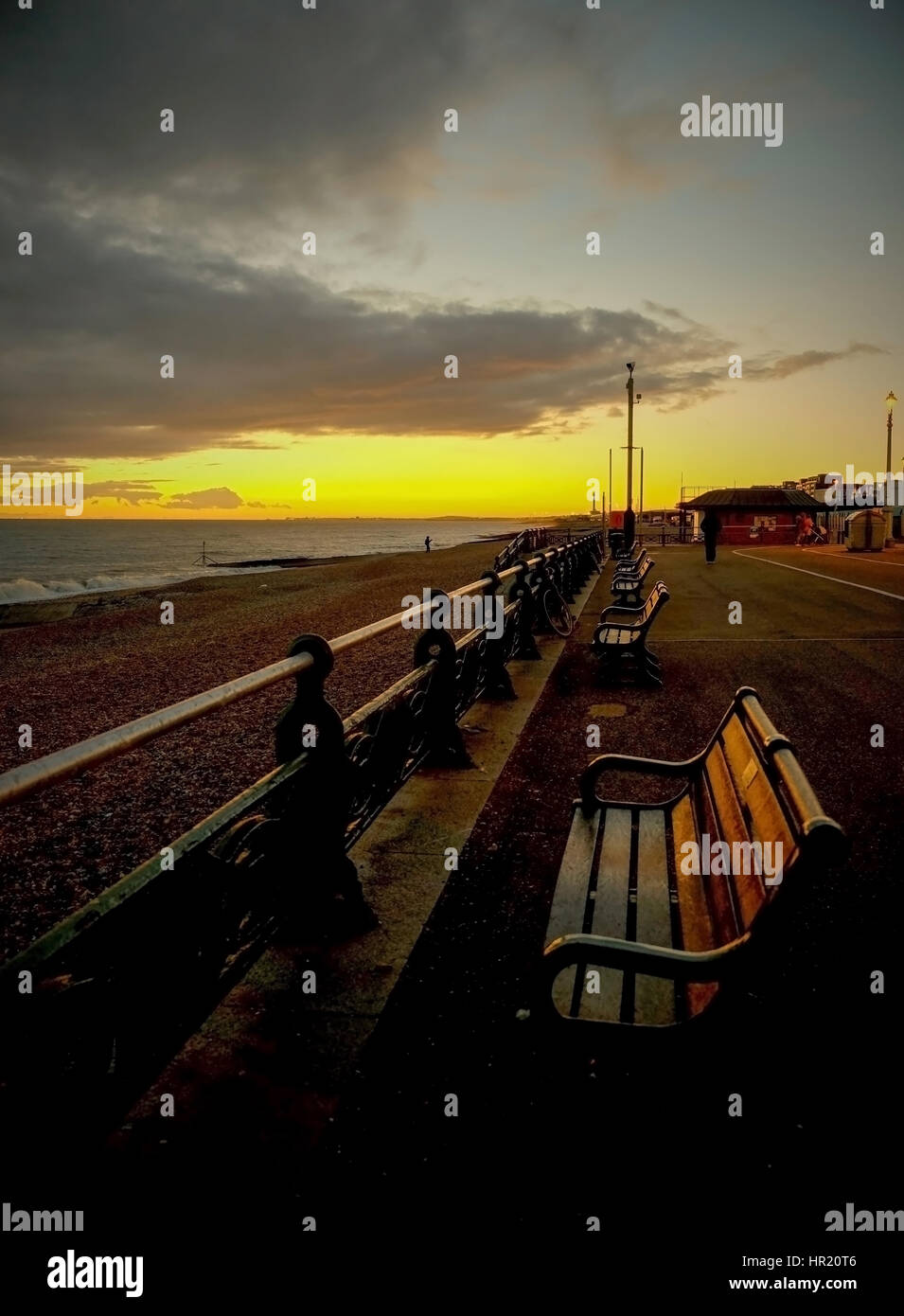 a line of wooden seats along a seafront promenade, the first bench is ...