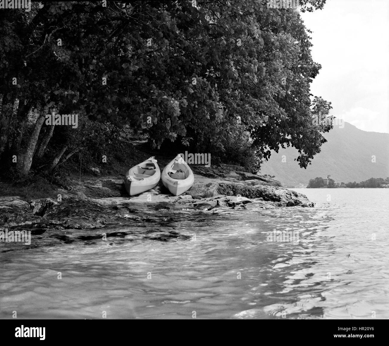 two canoes on tiny beach on edge of lake under trees, the lake is in ...