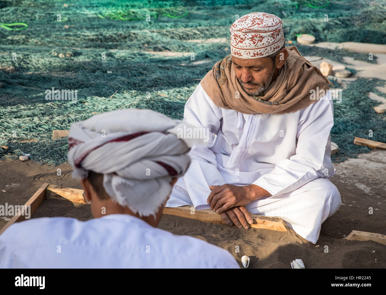 Muscat, Oman - Feb 4, 2017: Two traditionally dressed Omani men playing ...