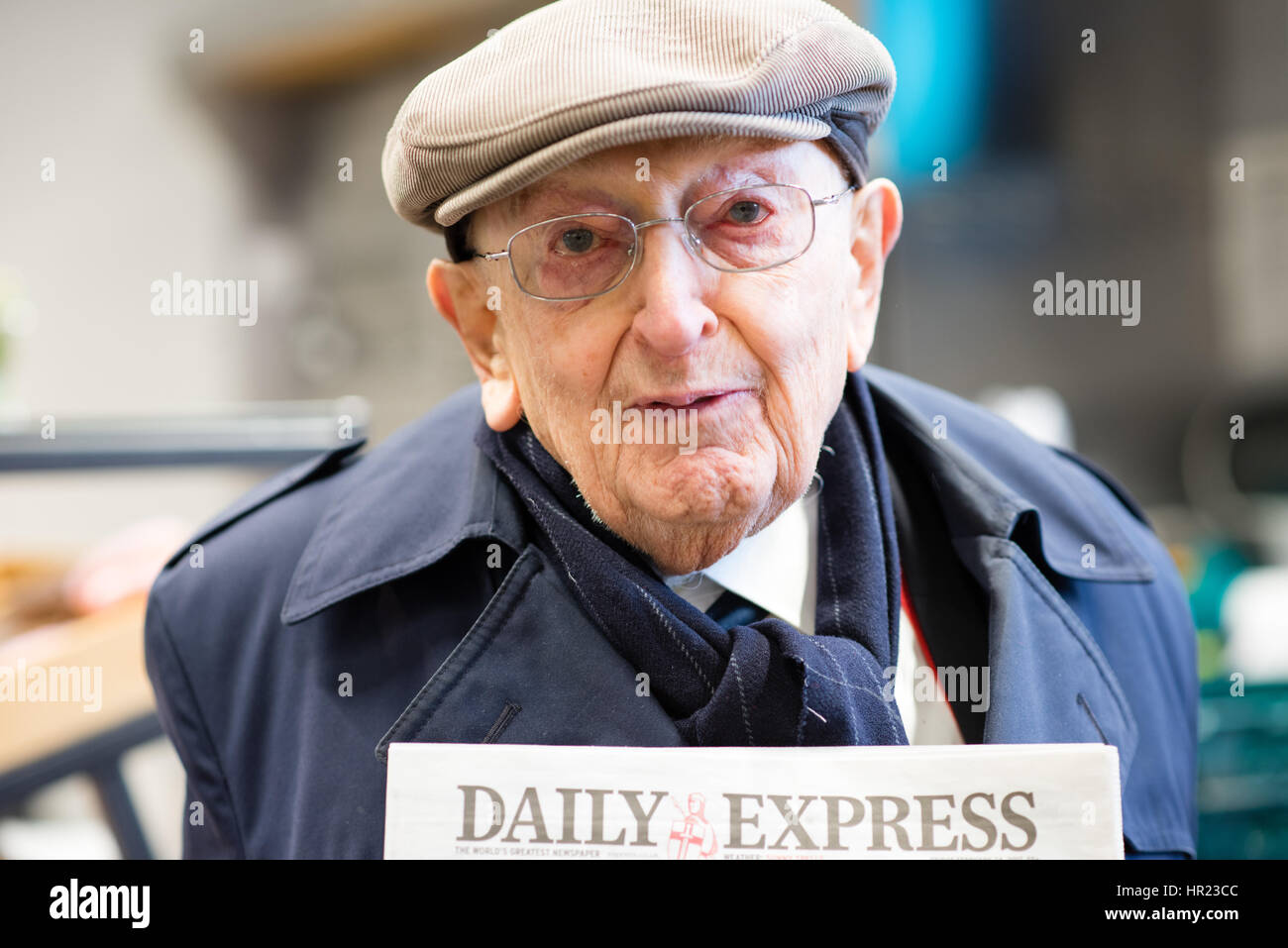 Portrait of a cloth cap wearing white old man holding up a copy of the ...