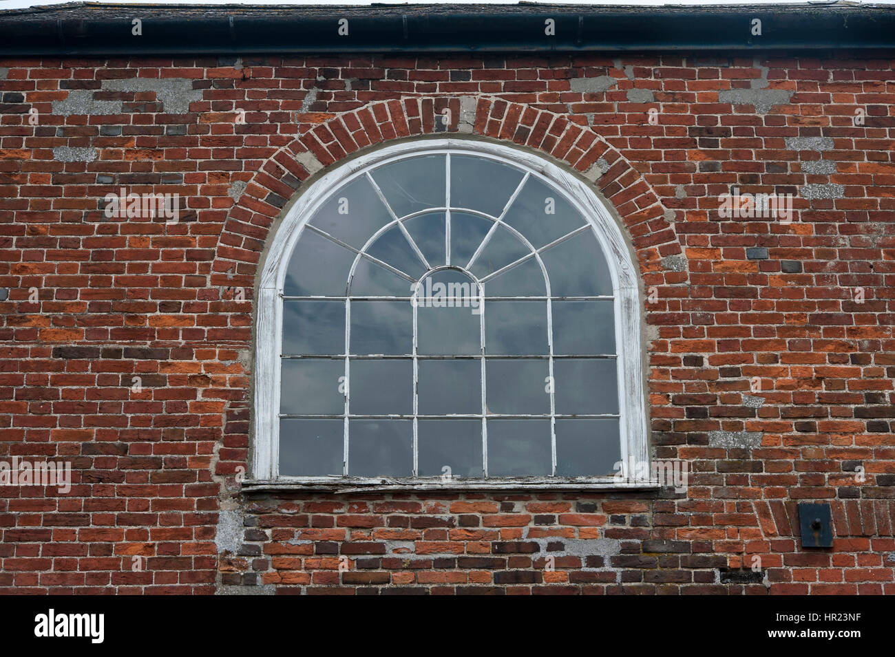 A large arch-topped window in the brick wall of an old brick building ...