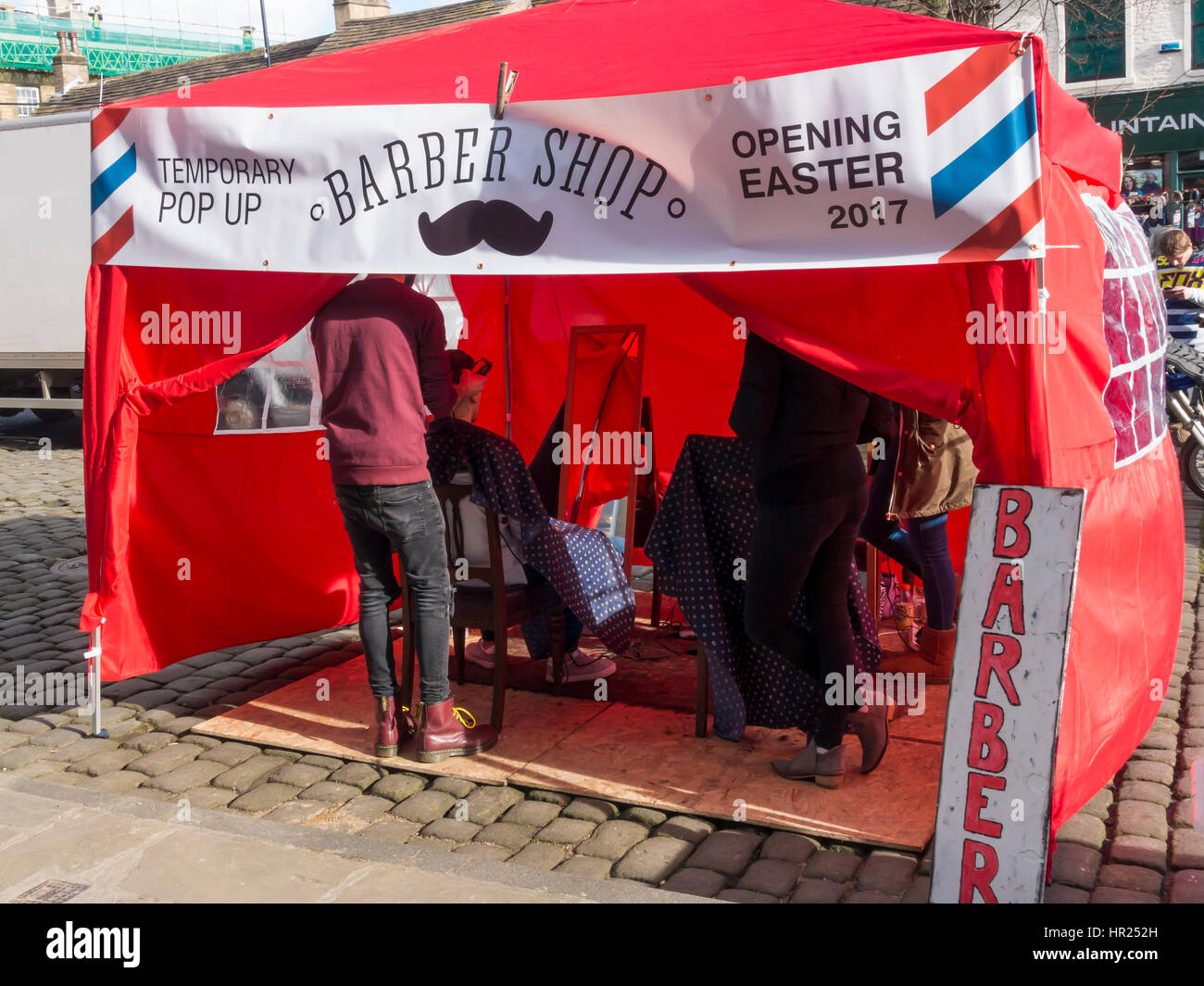 Two young men working as hairdressers at a Temporary Pop-Up Barber shop ...