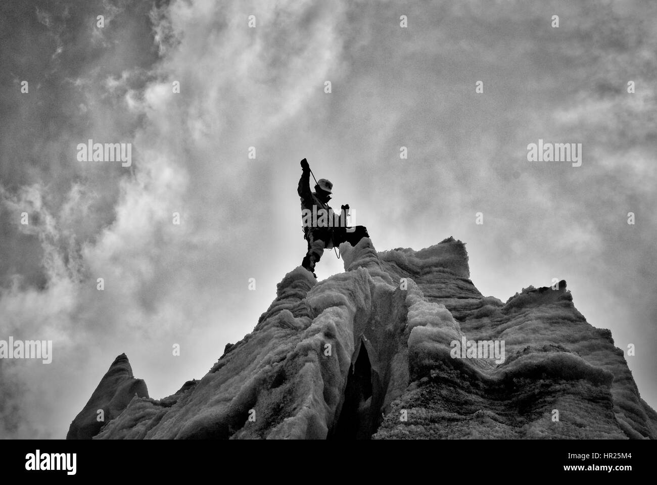 Dramatic lighting on a climber coiling rope at the top of a climb Stock ...