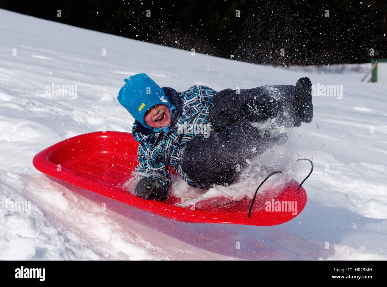 A young Boy (4 yrs old) jumping into the air on a sledge in Quebec ...