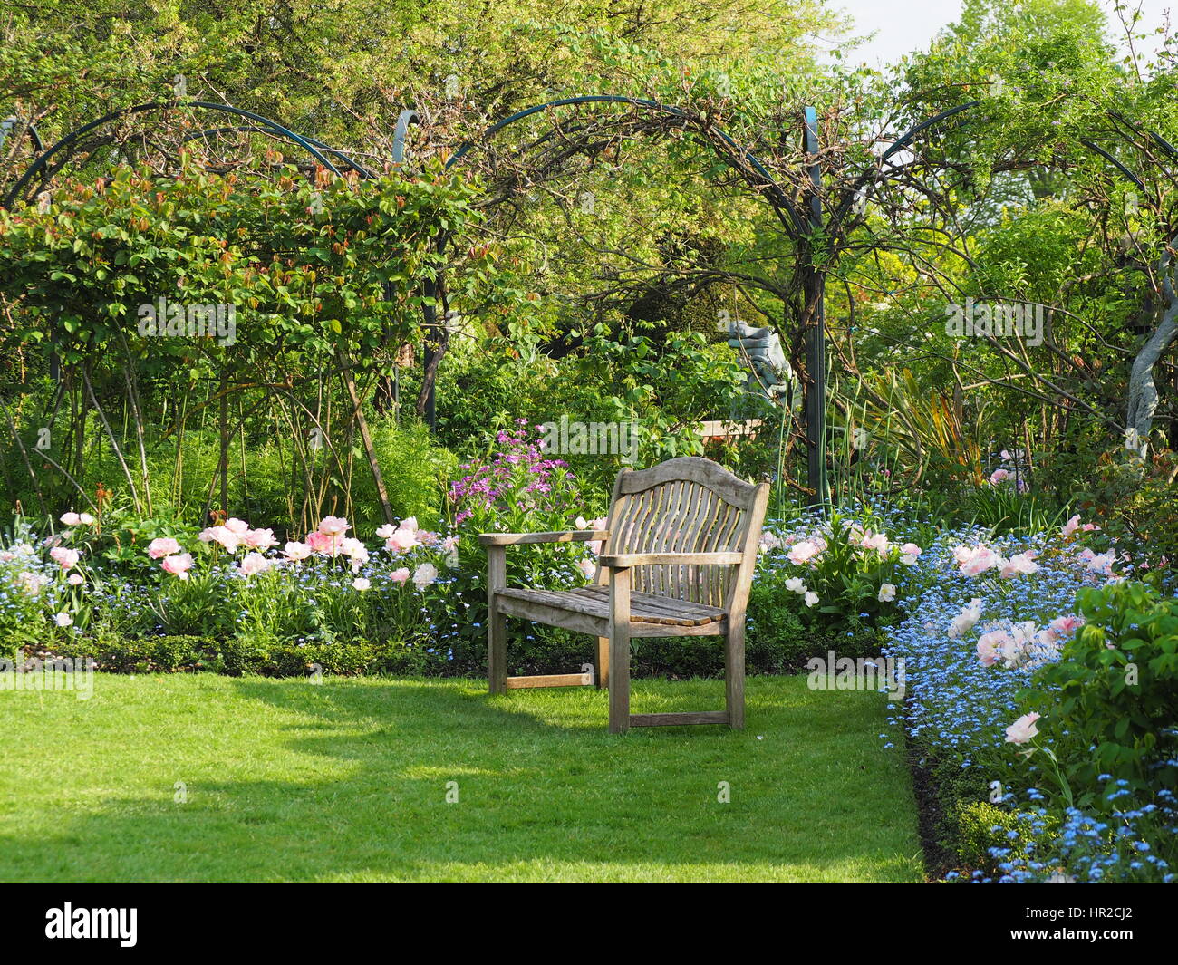 Garden bench in Chenies Manor Garden in May showing the awn, archway ...