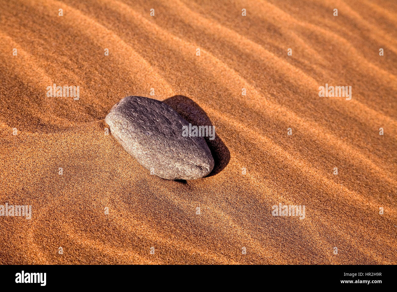 stone lying on a beach changing the natural sand pattern Stock Photo ...