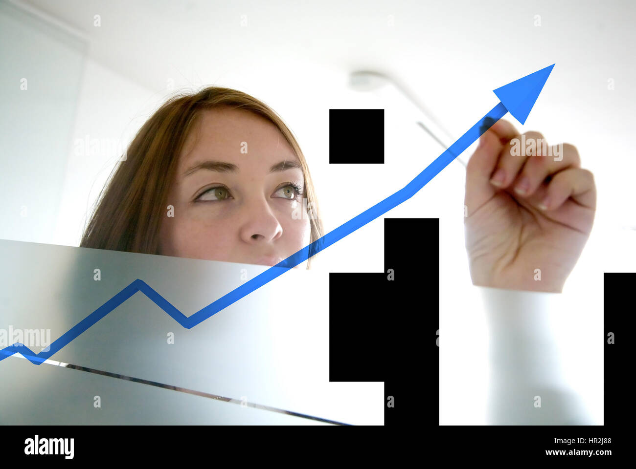 business woman drawing a graph on a glass window in an office - focus ...
