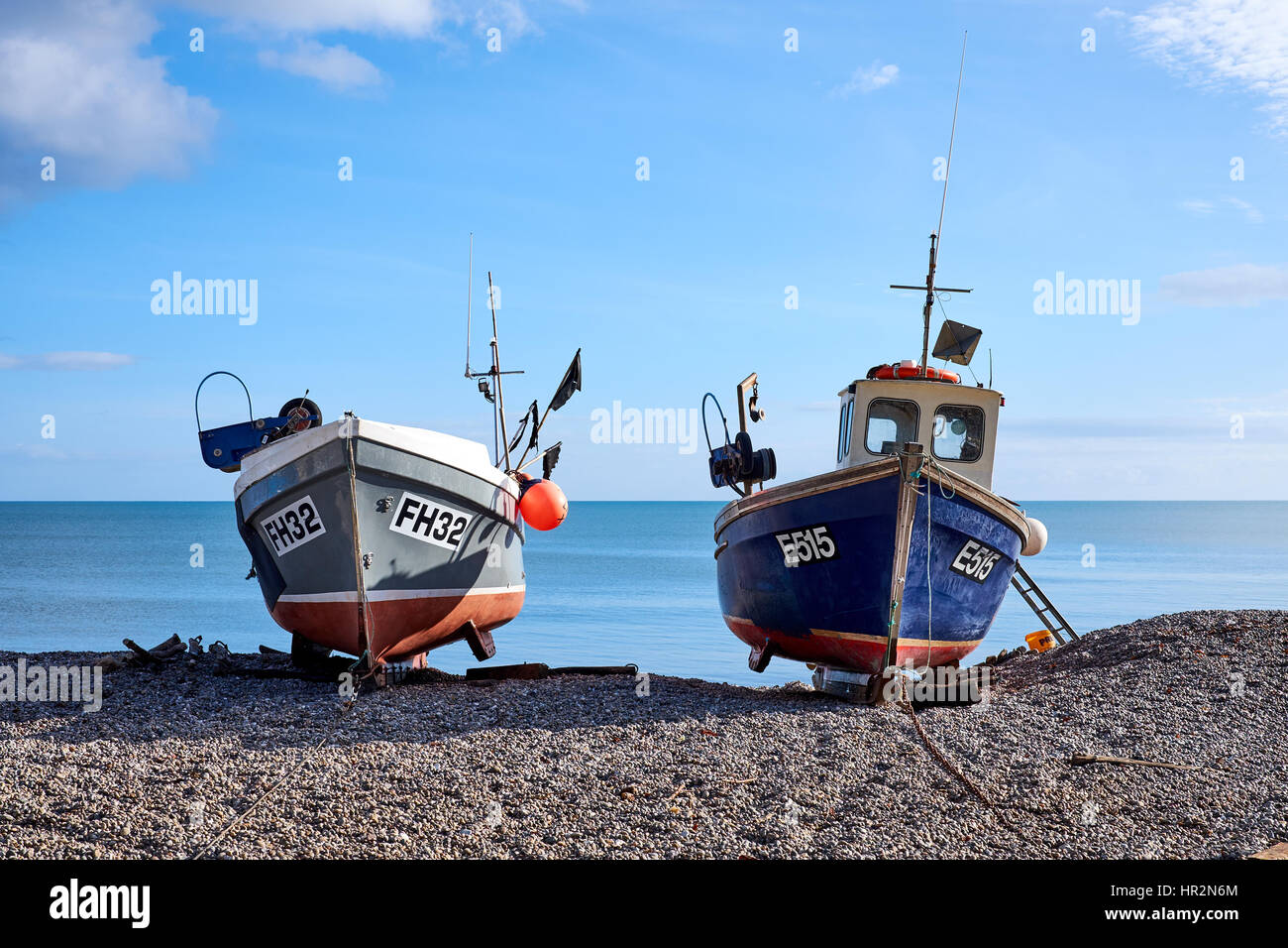 Two fishing boats sit on the pebble beach at Beer in Devon on a clear ...