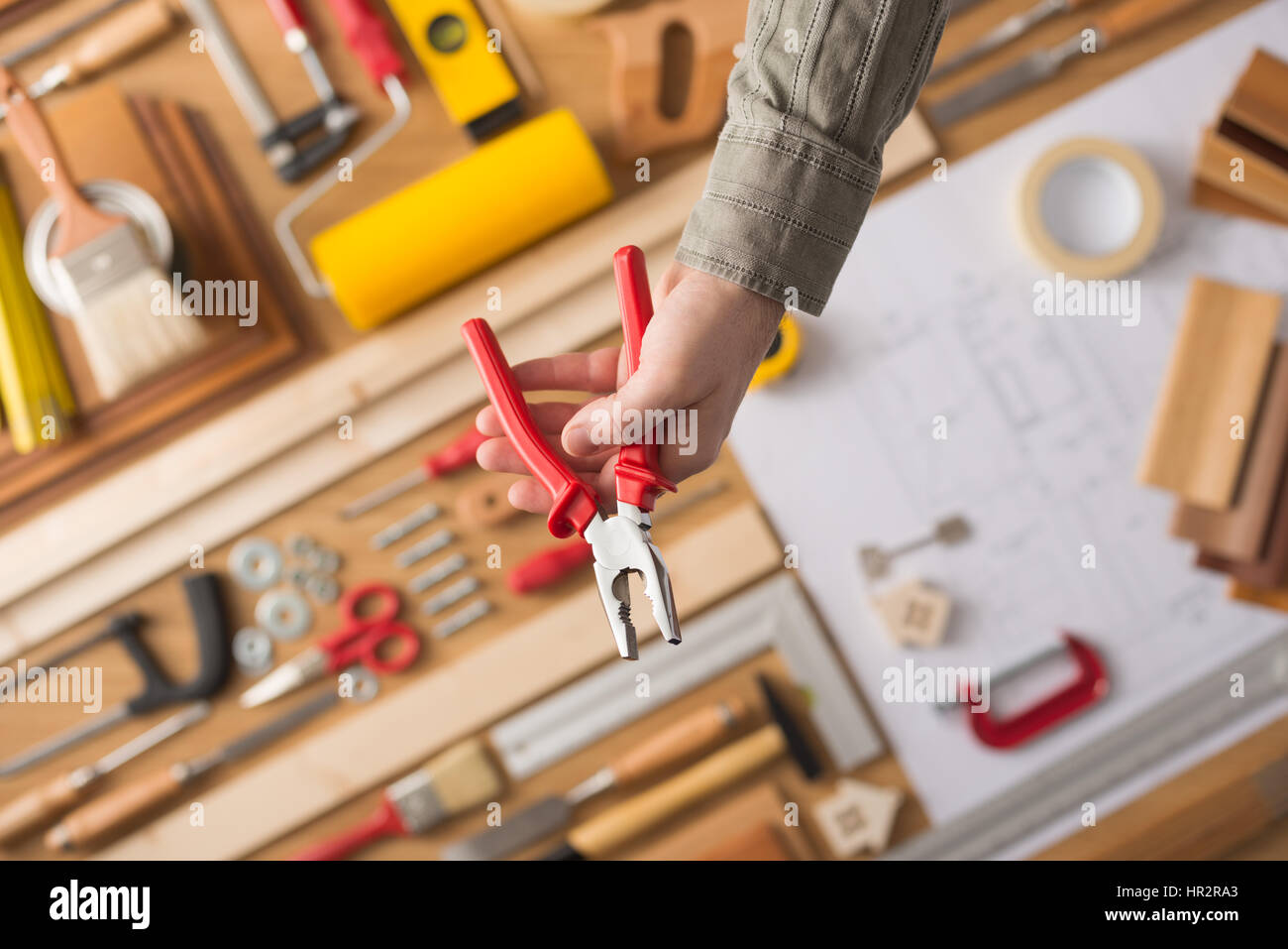 Male hand holding pliers, work table with construction and repair tools ...