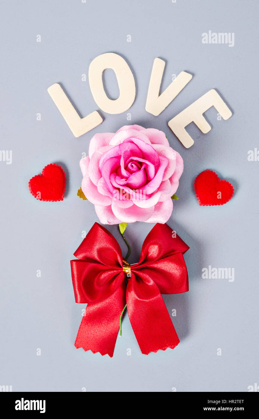 Pink rose and love word with red bow on gray background Stock Photo - Alamy