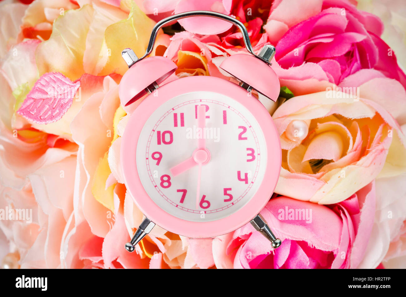 Pink alarm clock on bouquet pink rose background Stock Photo - Alamy