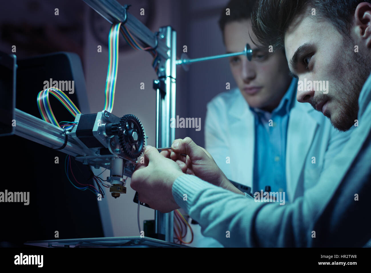 Engineering team working on a 3D printer, a student is adjusting the ...