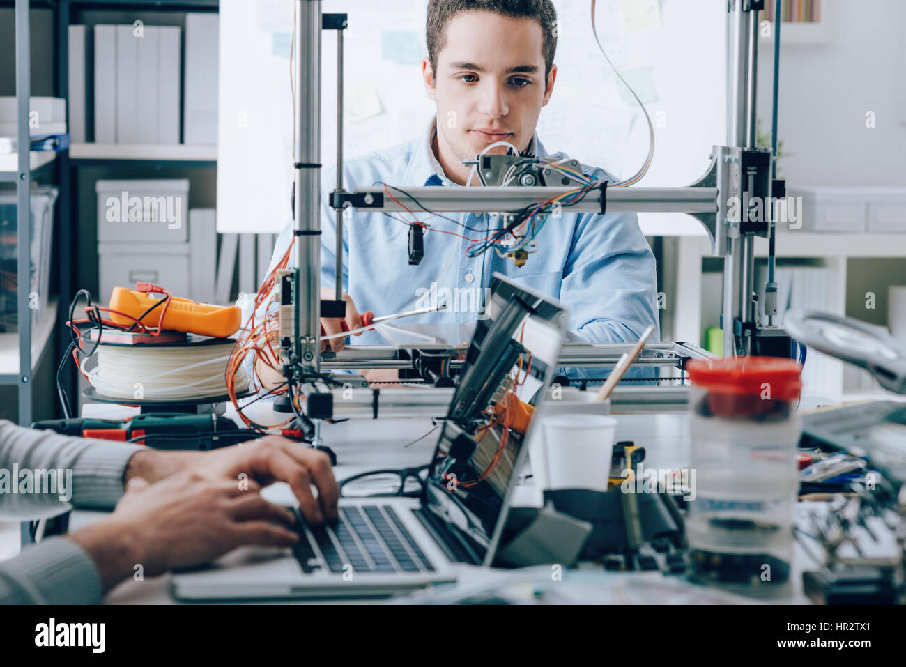Students sitting at the laboratory desk and using a 3D printer for ...