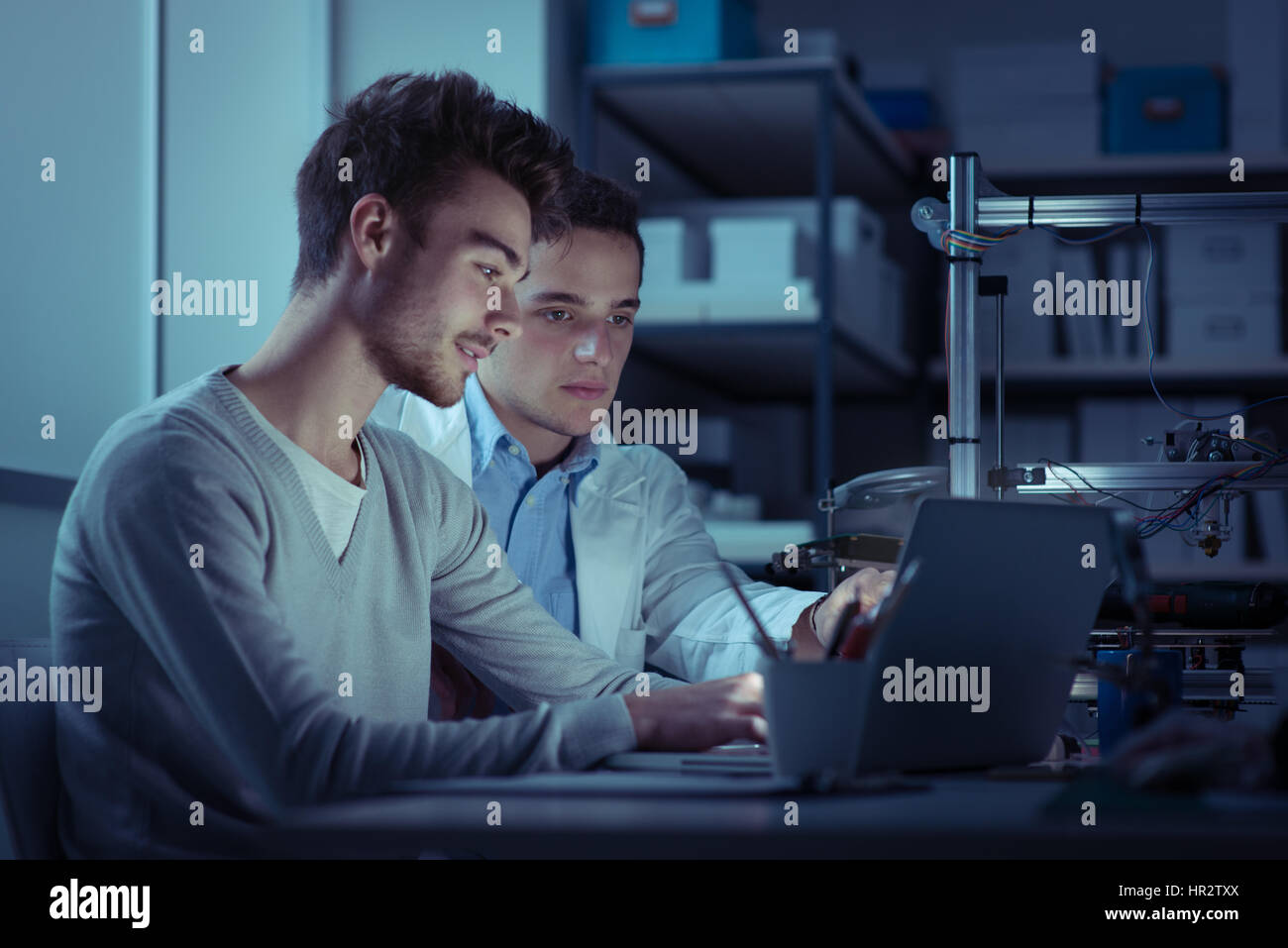 Engineering students in the lab at night, they are using a laptop and ...