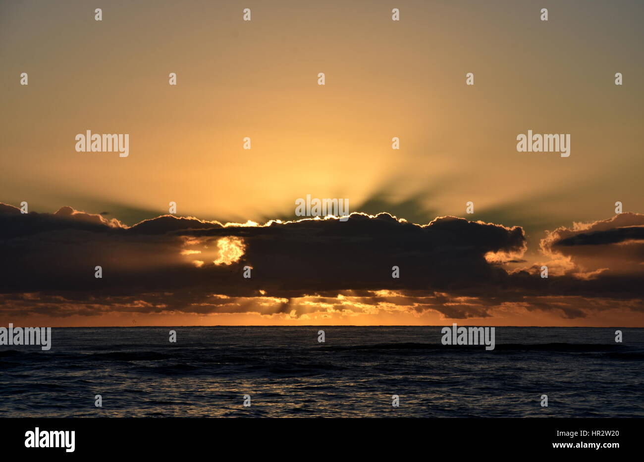 Beautiful sunrise cloudscape over ocean background. Sun rays beaming ...