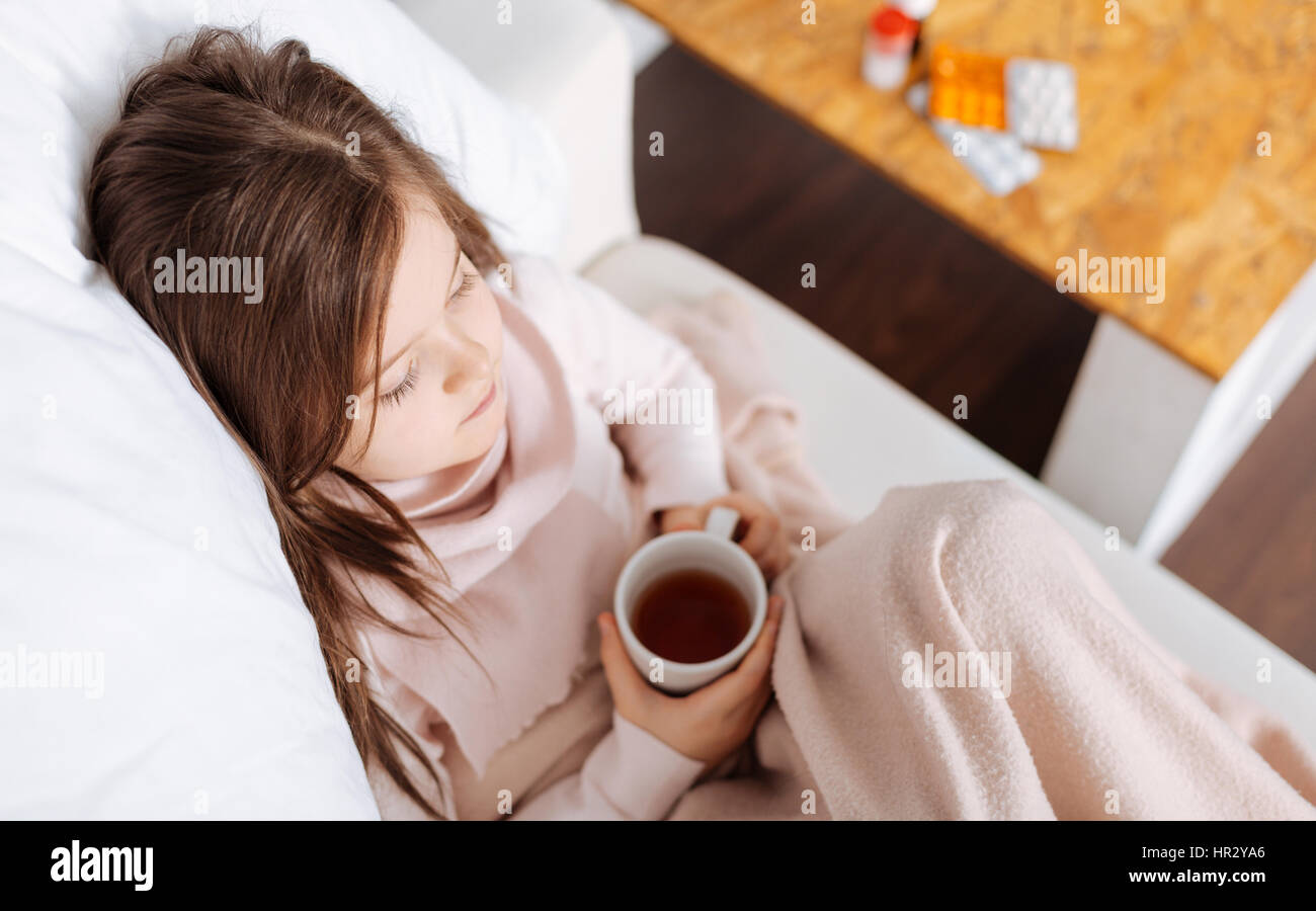 Regular medication. Pleasant ill girl drinkign tea and feeling sick ...