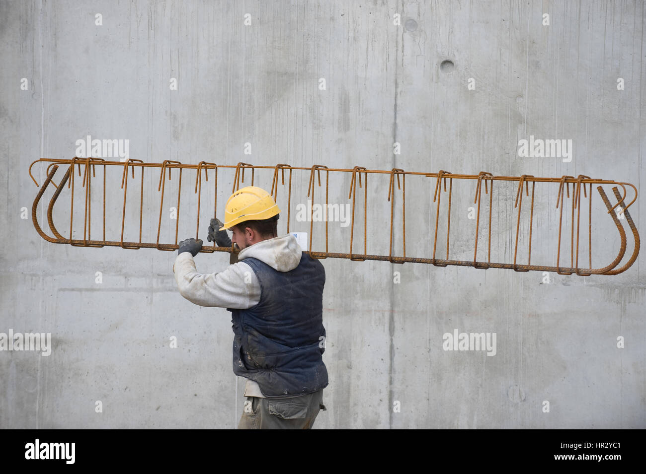 Construction worker carrying reinforcement rods on the shoulder, France ...