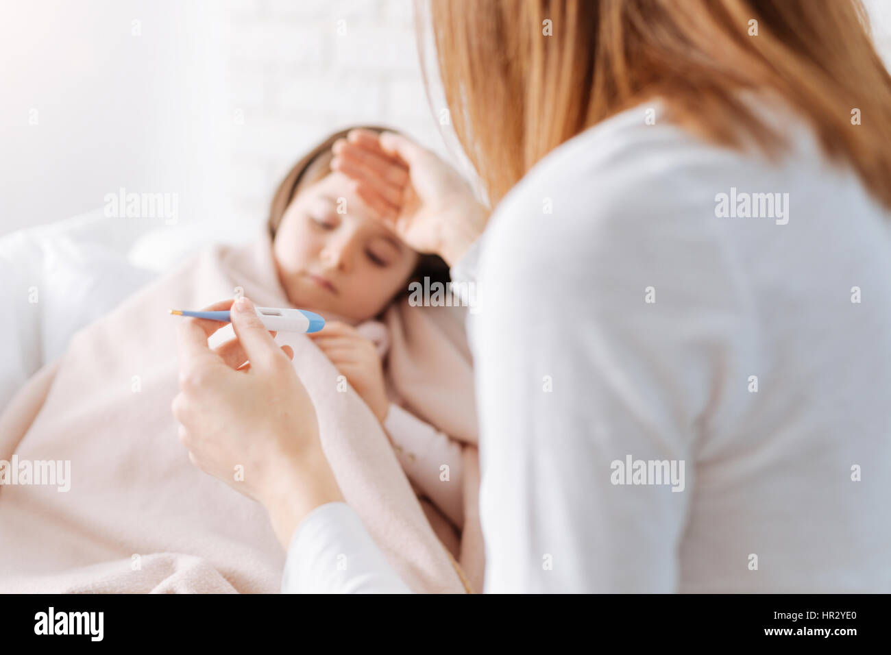 Quick help. Cheerless sick little girl lying in bed and feeling ill ...