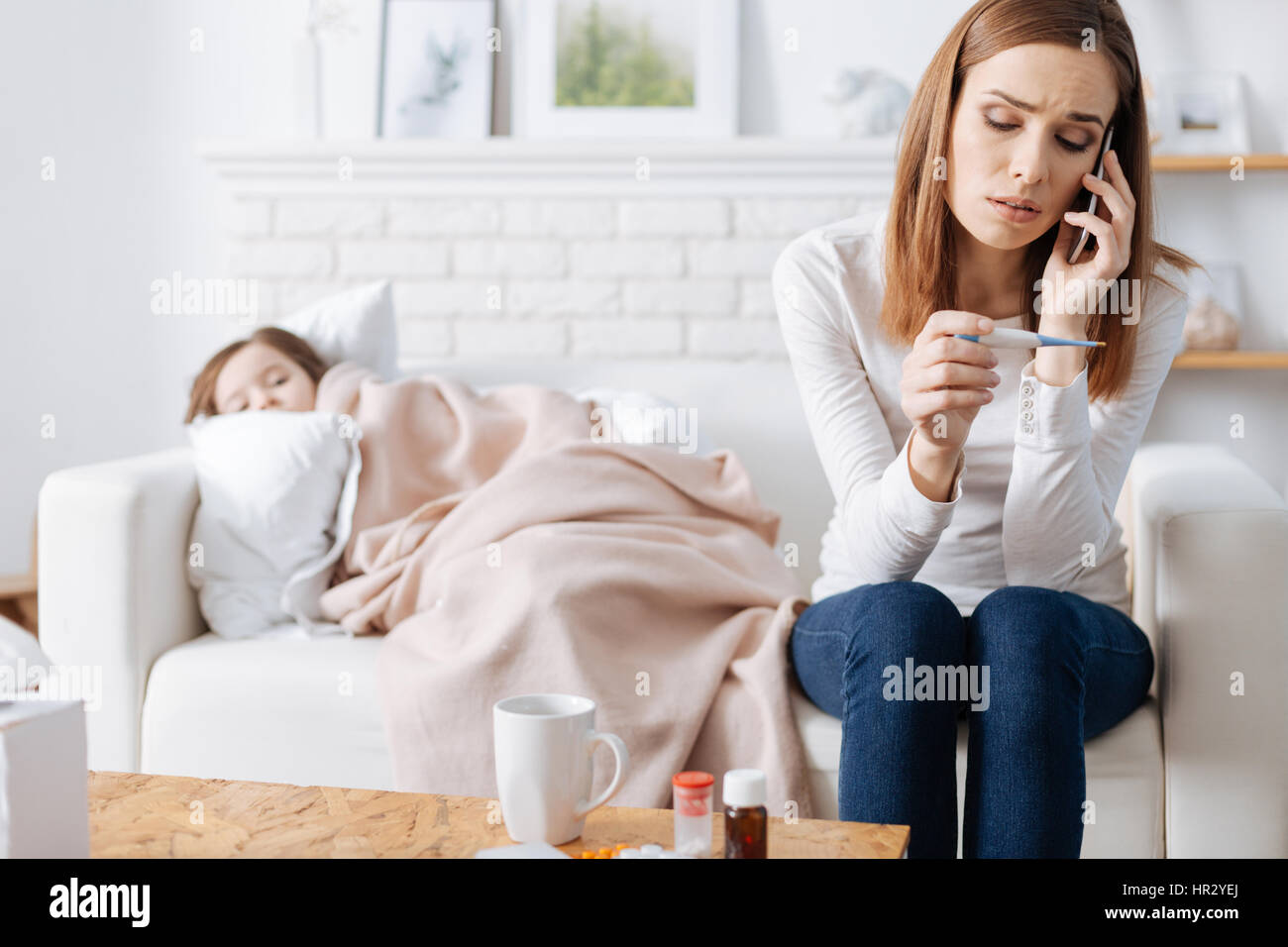 We have troubles. Troubled caring mother calling a doctor while her ...