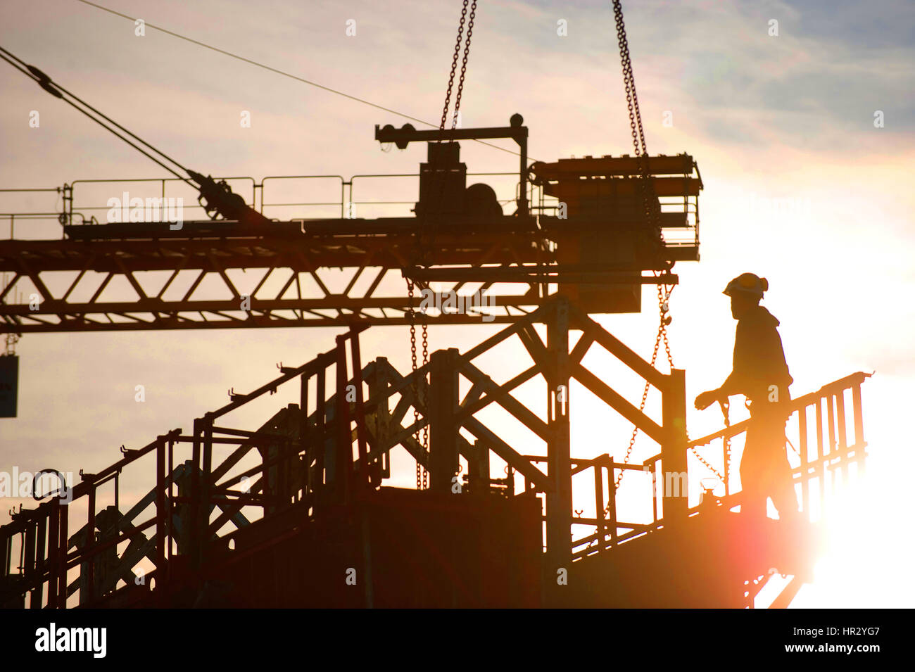 Construction worker, crane and building at sunset, France Stock Photo ...