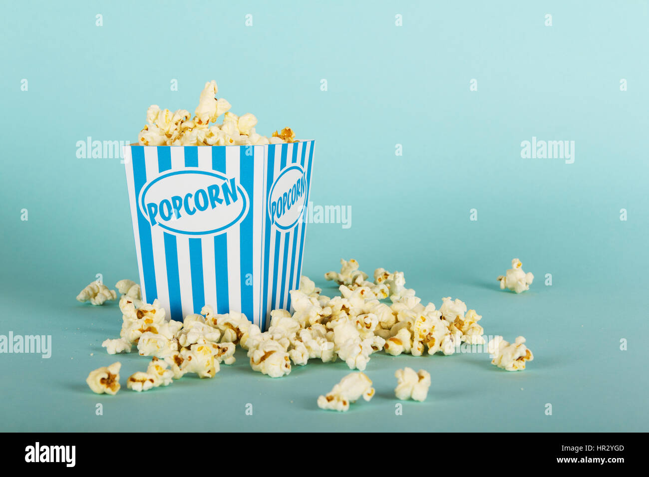 Bucket of popcorn against a blue background Stock Photo - Alamy