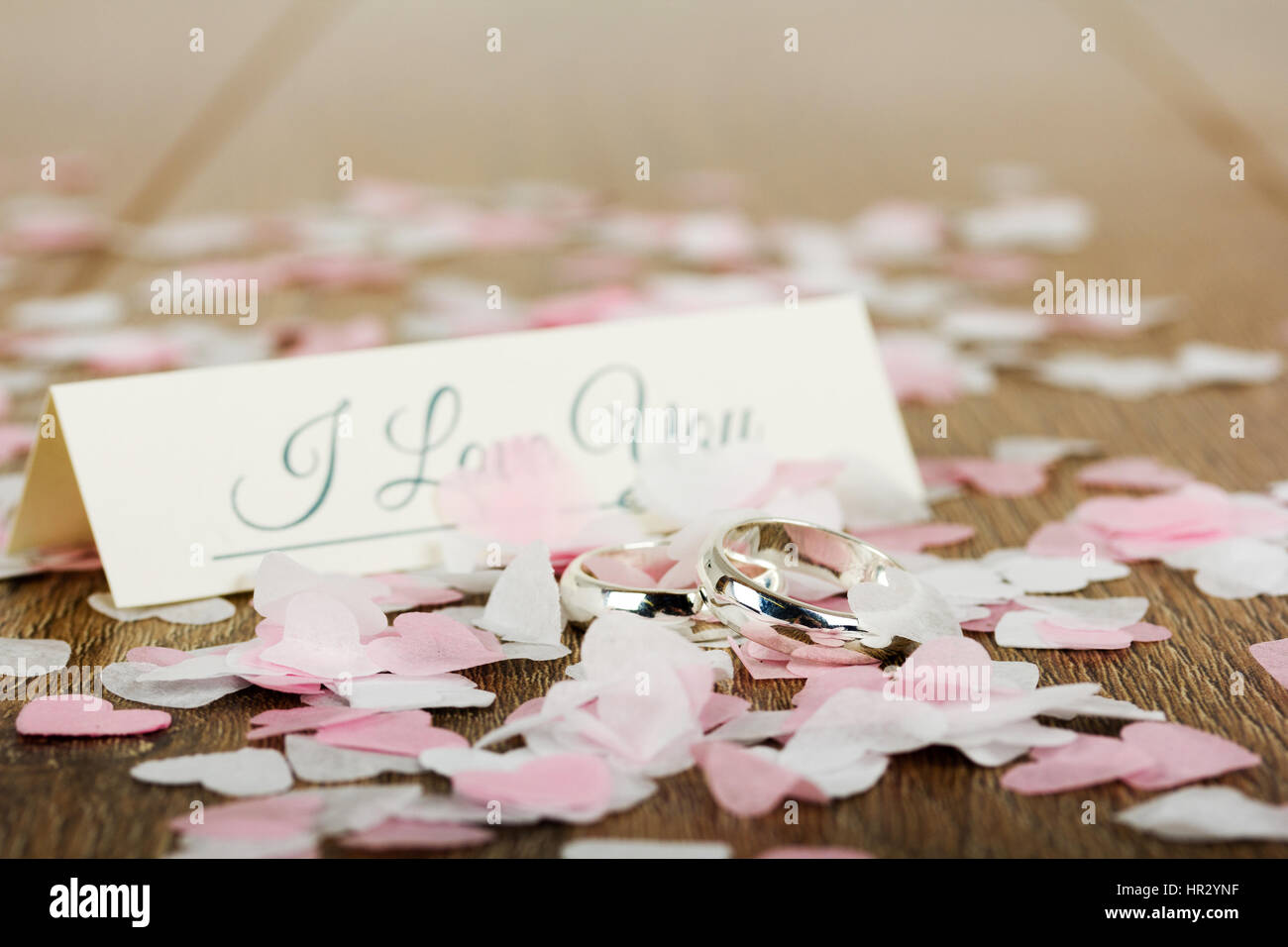 pair of white gold wedding rings on a wooden background with confetti ...