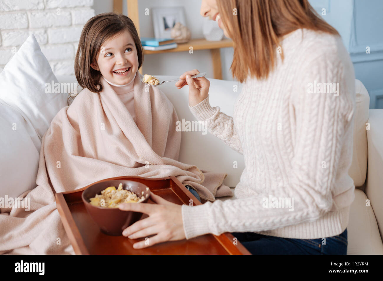Rise your mood. Joful cute little girl smiling and eating breakfast ...