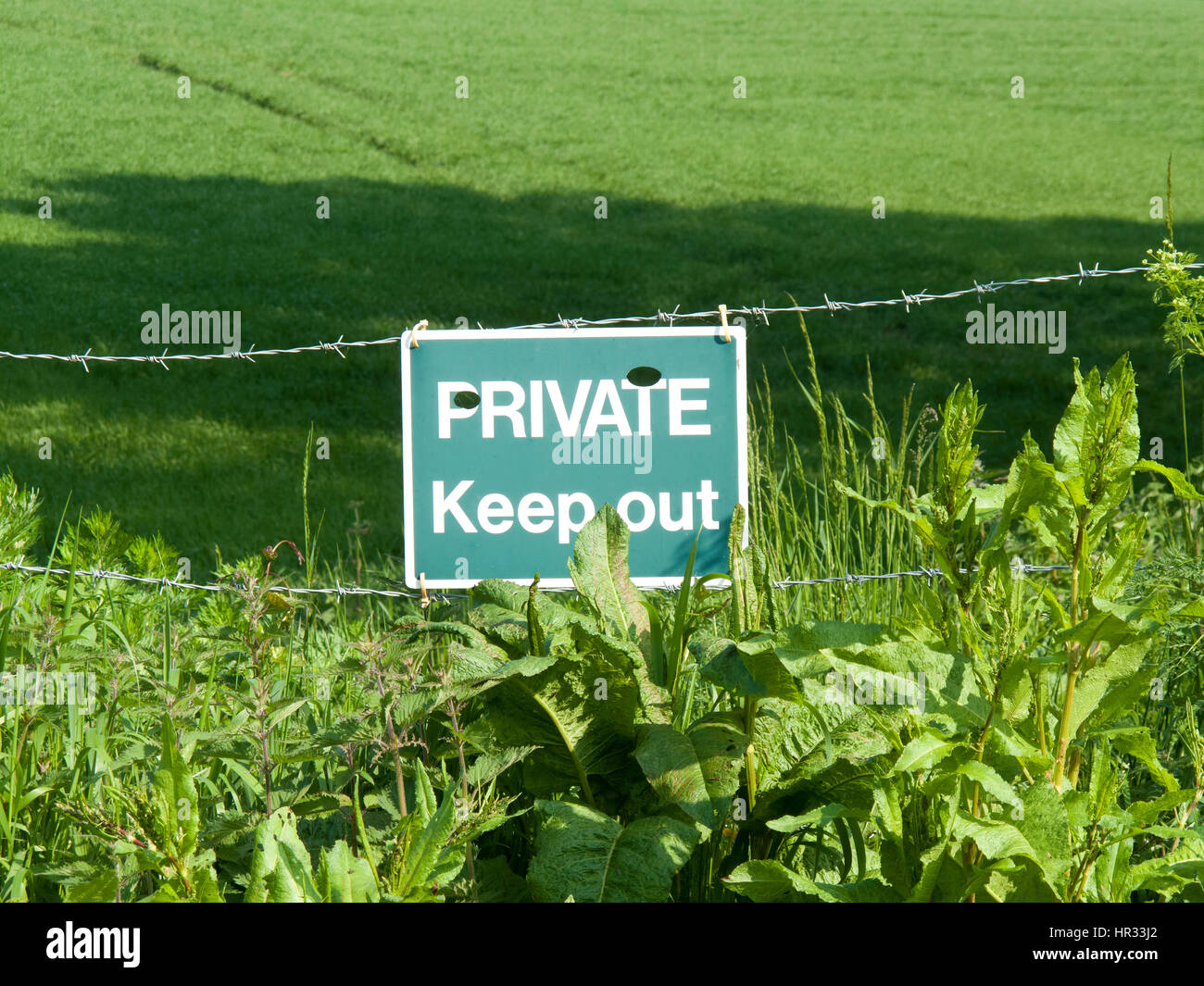 Private keep out sign on barbed wire boundary fence to farmland Stock ...