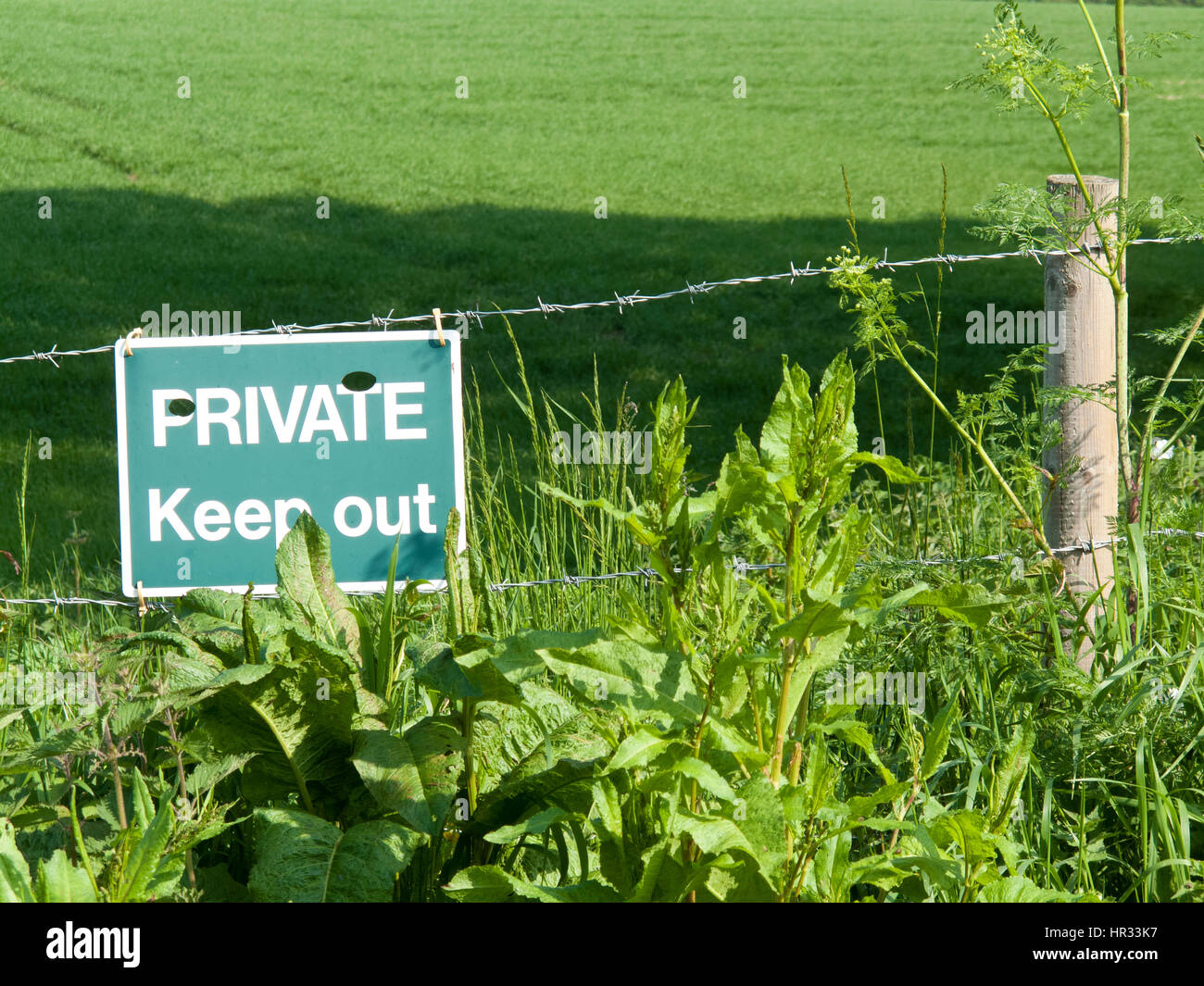 Private keep out sign on barbed wire boundary fence to farmland Stock ...