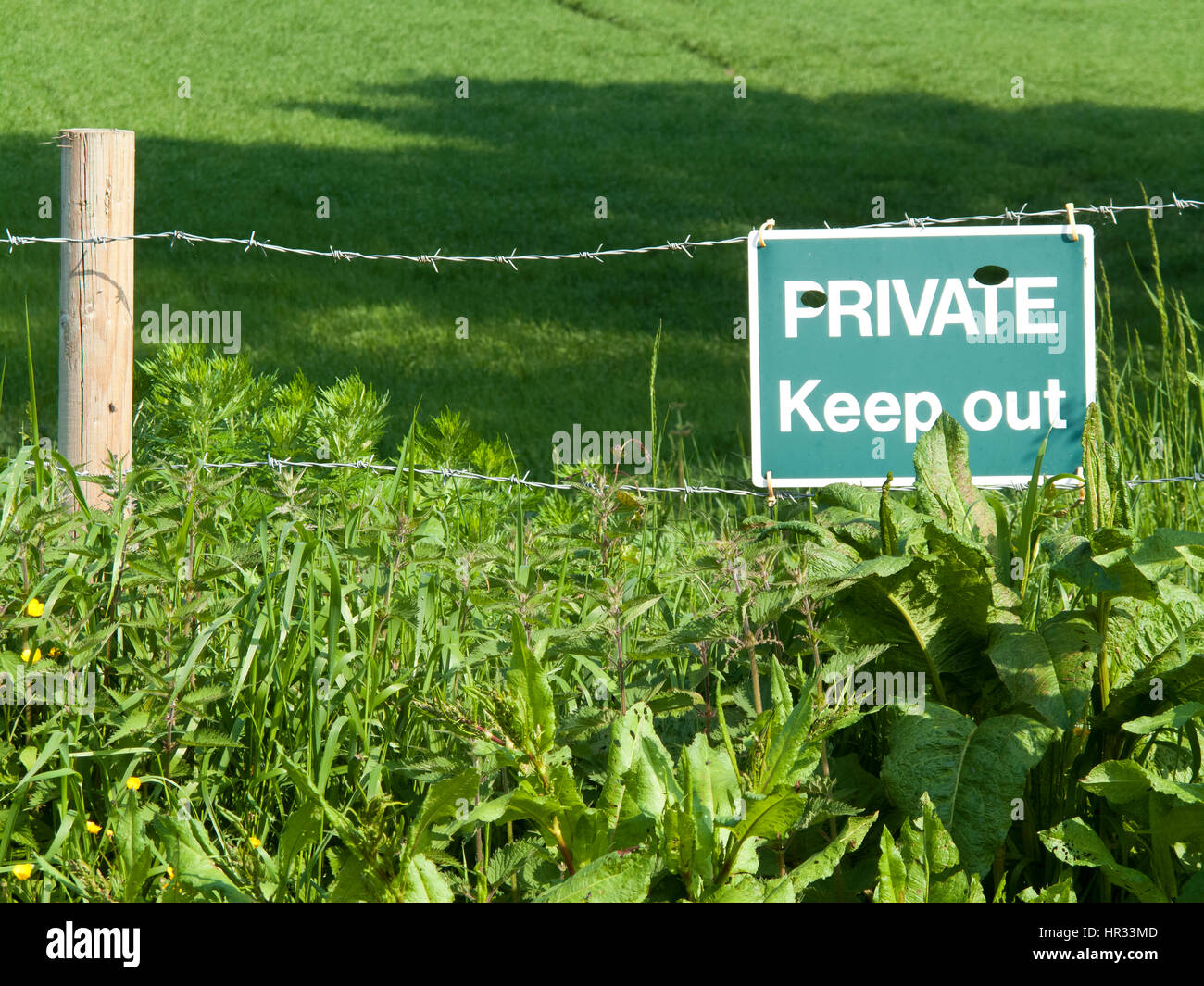 Private keep out sign on barbed wire boundary fence to farmland Stock ...