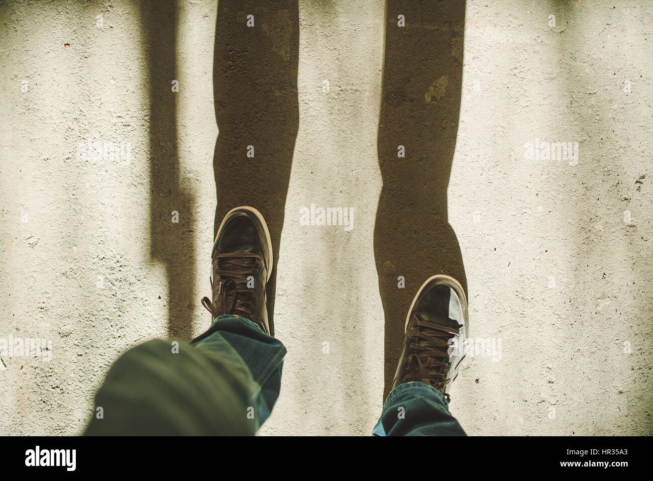 Two feet in brown shoes over concrete, first person view with bright ...