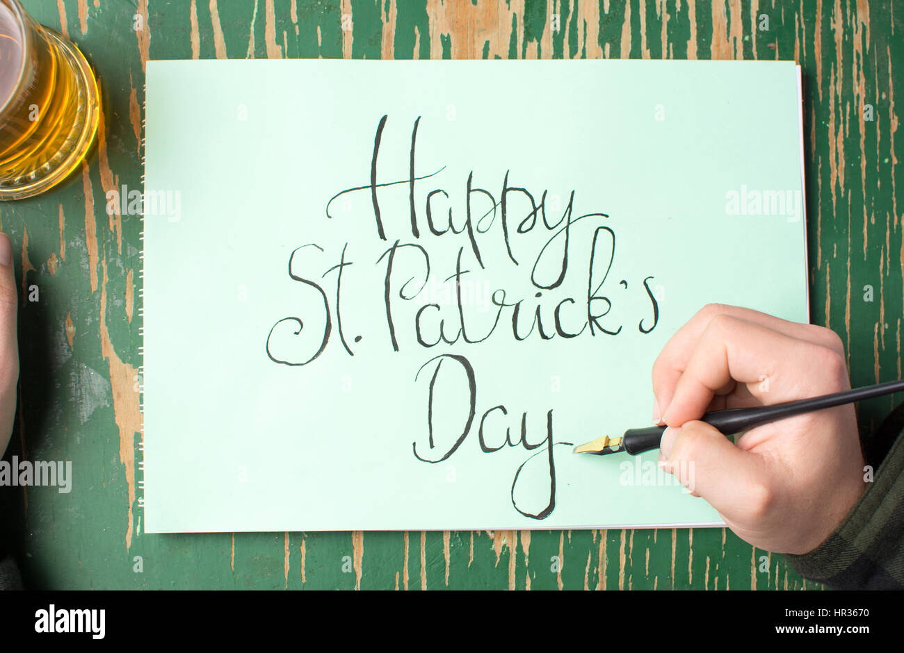 Man writing a Happy St Patrick day calligraphy card Stock Photo - Alamy