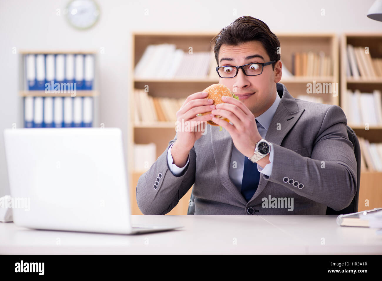 Hungry funny businessman eating junk food sandwich Stock Photo - Alamy