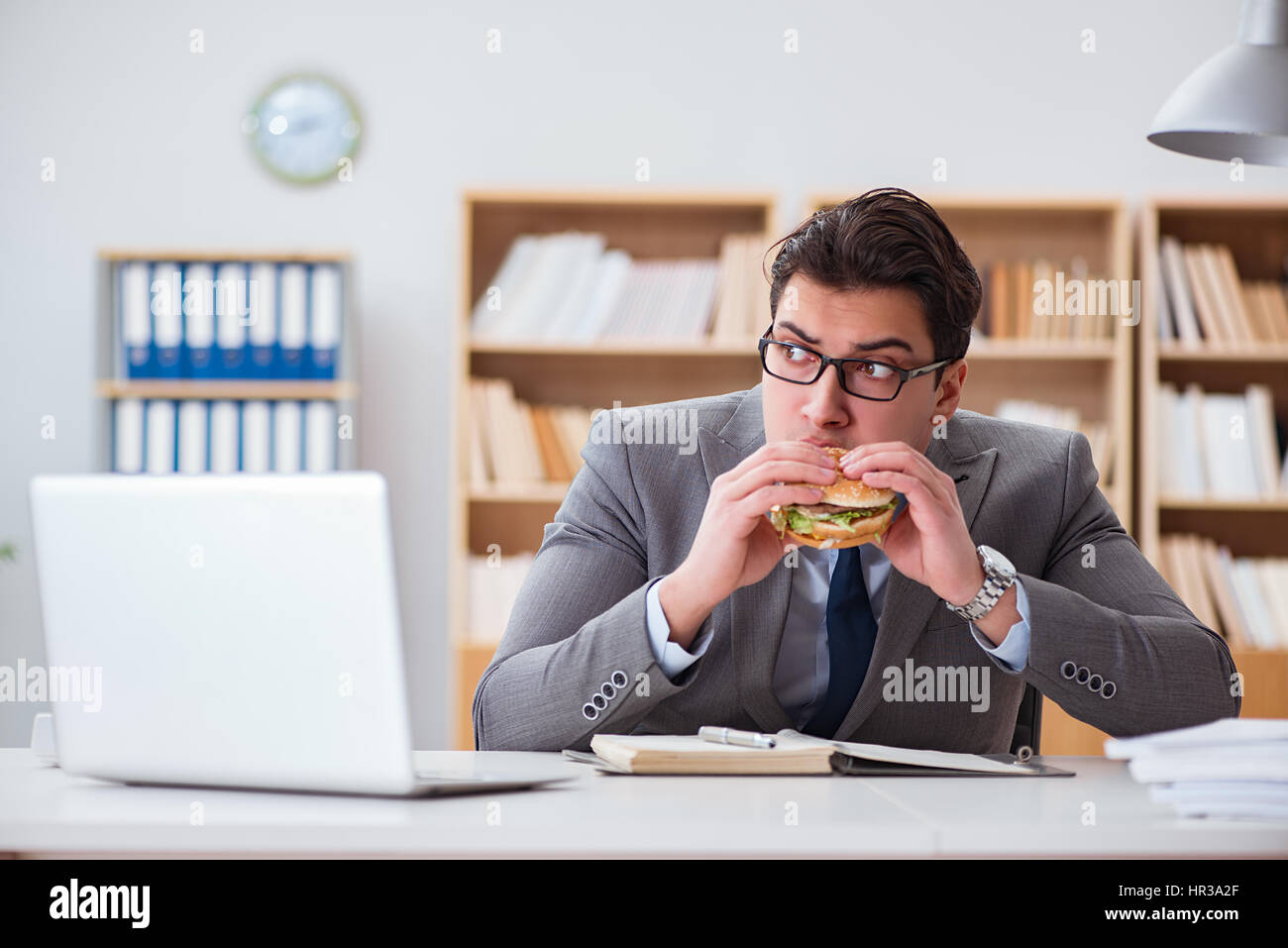 Hungry funny businessman eating junk food sandwich Stock Photo - Alamy